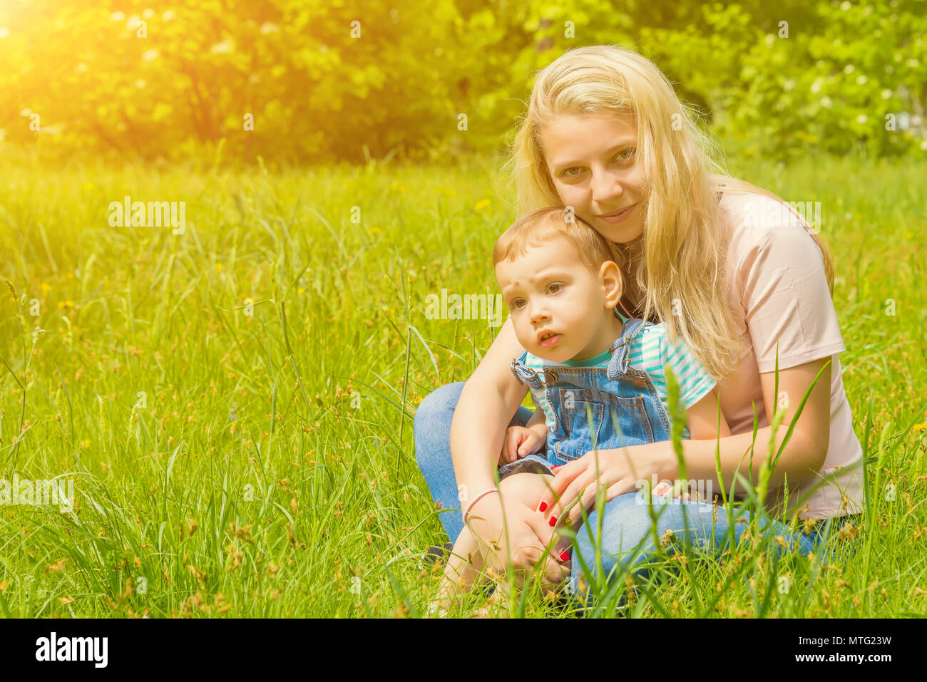 mother and child in nature in the Park, resting on the green grass in ...