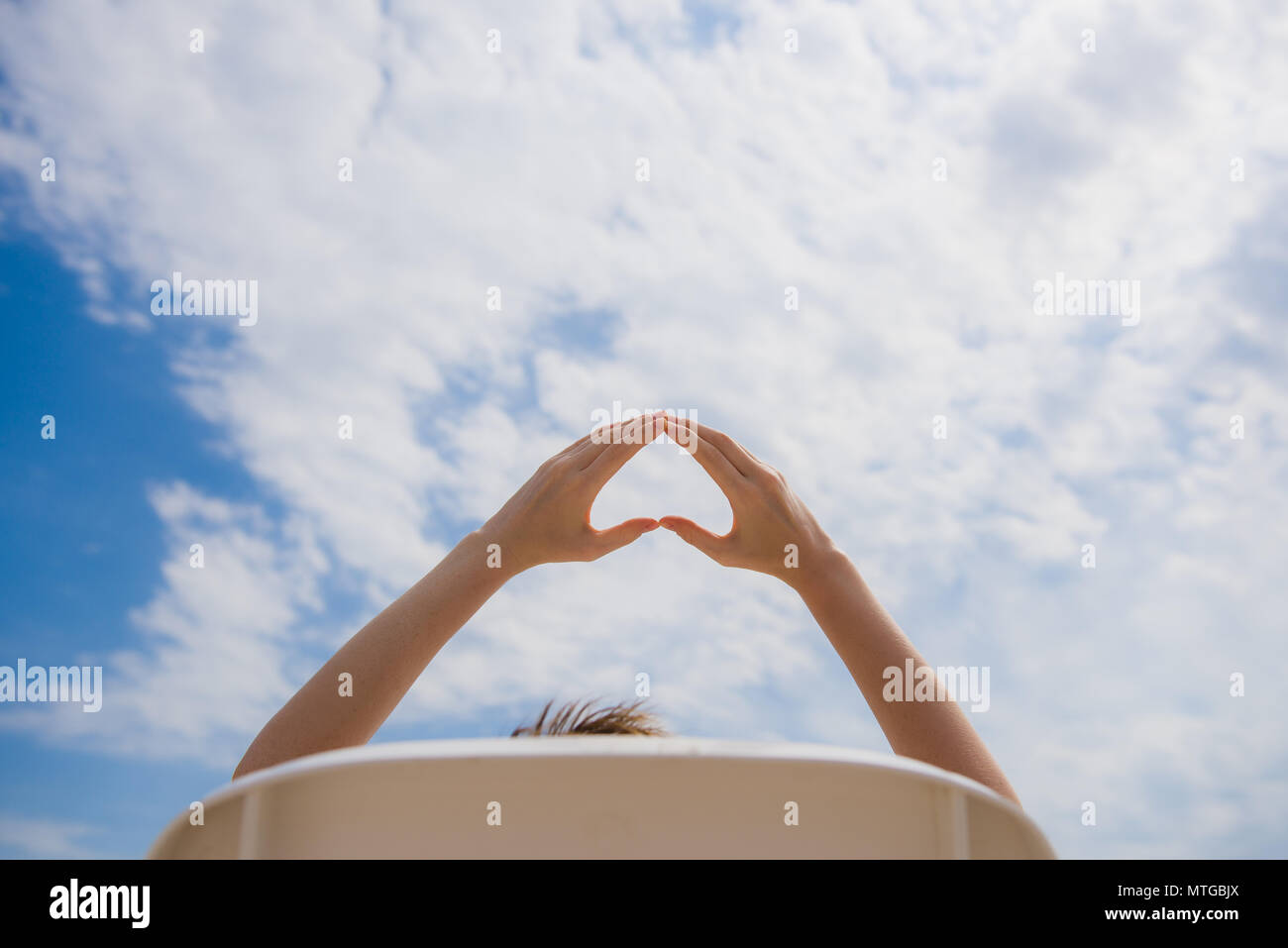 Female hands make heart form outdoors. Woman making heart figure at sky ...