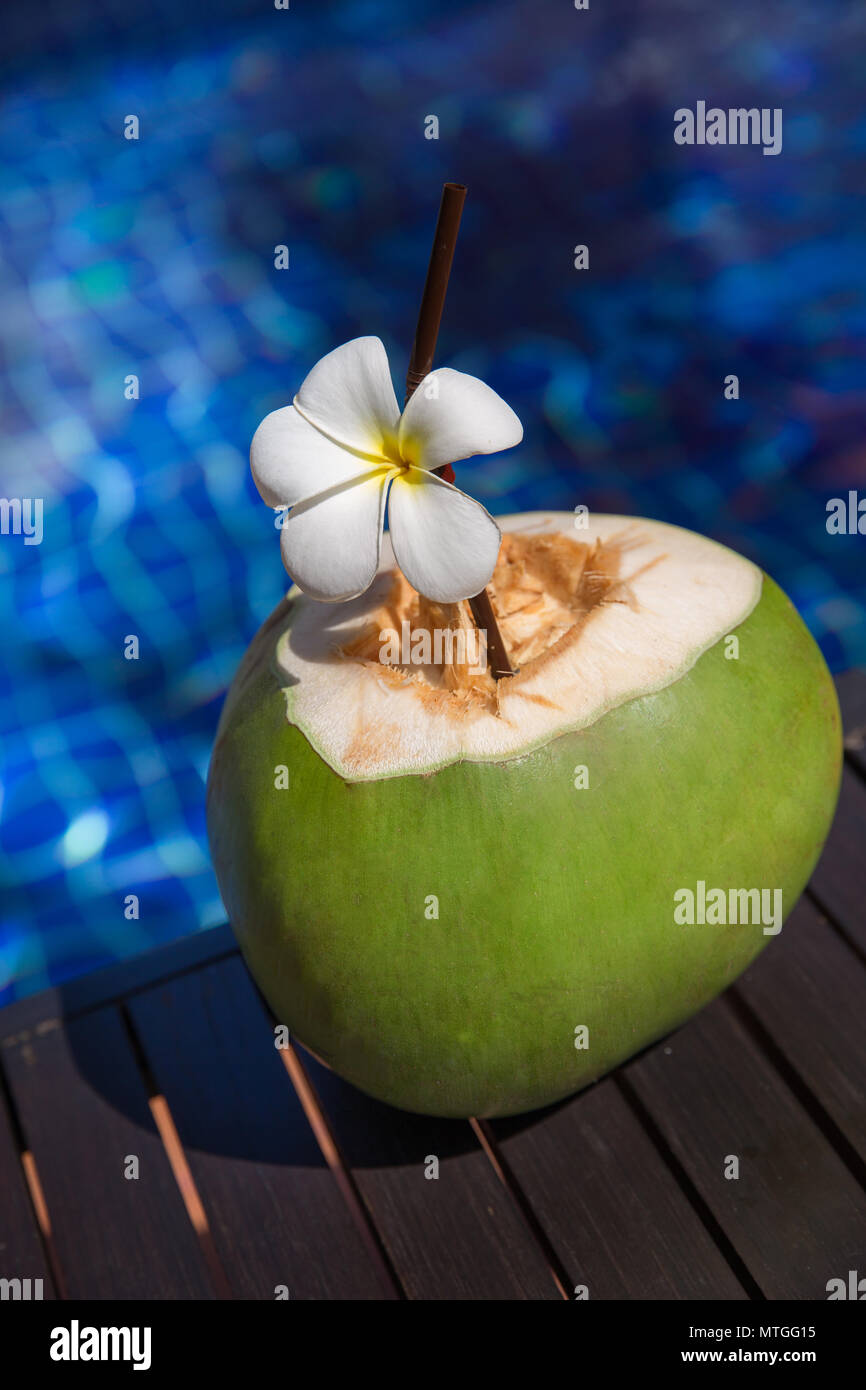 Fresh coconut juice with straw and plumeria, frangipani, flower on ...