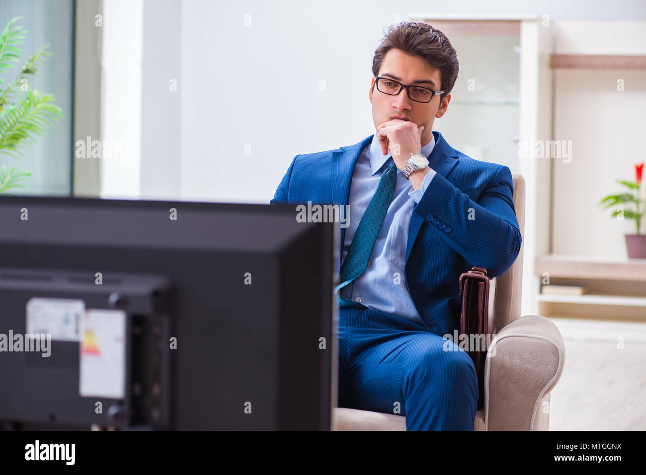 Businesman watching tv in office Stock Photo - Alamy