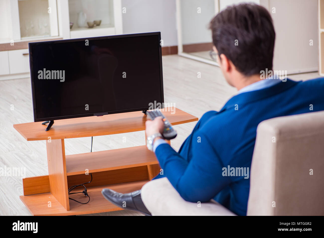 Businesman watching tv in office Stock Photo - Alamy