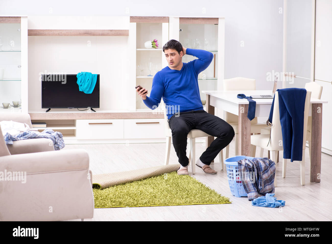 Young man collecting dirty clothing for laundry Stock Photo - Alamy