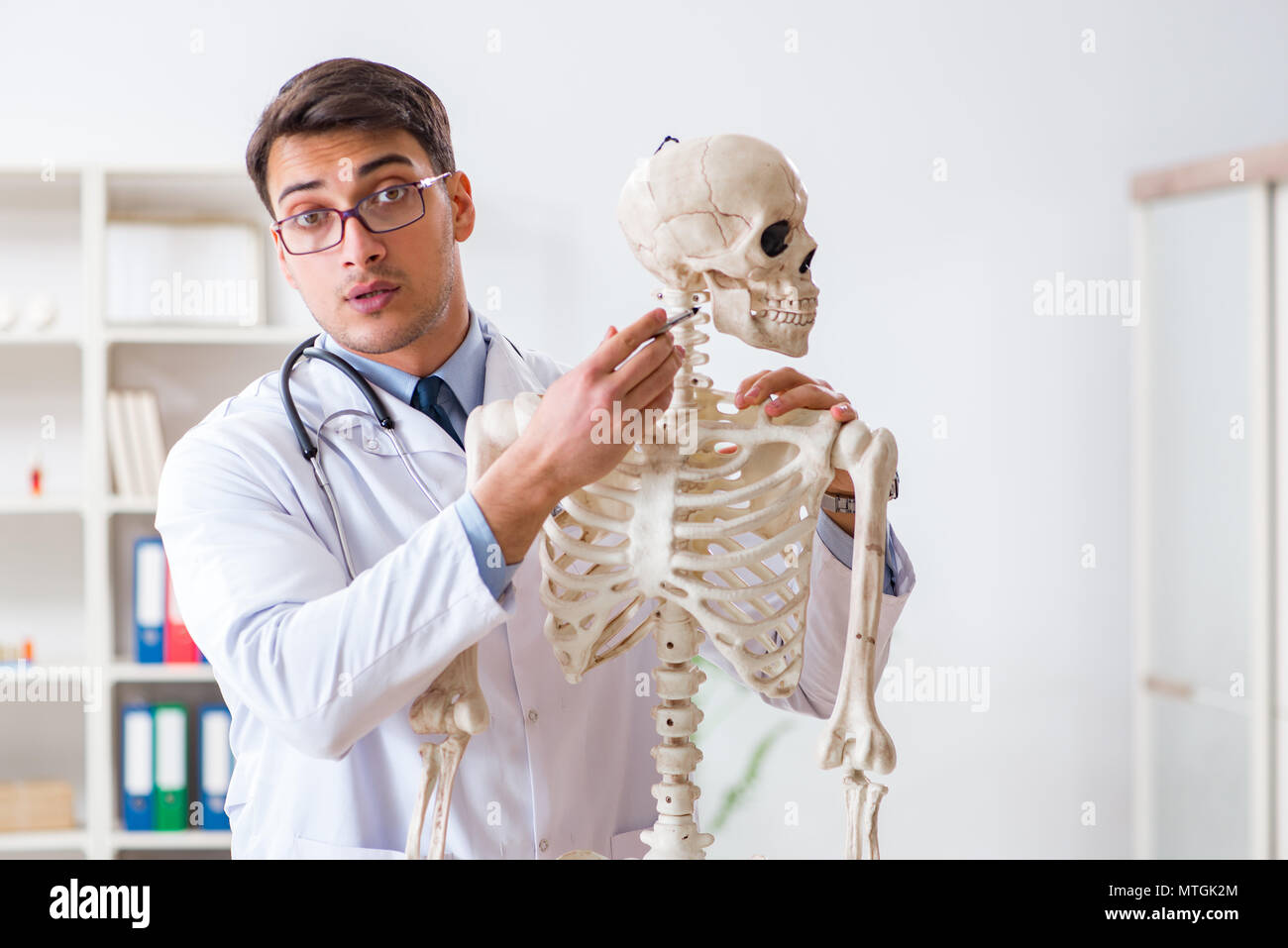 Yong male doctor with skeleton isolated on white Stock Photo - Alamy