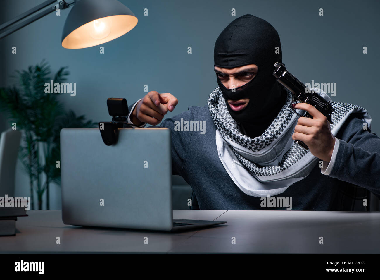 Terrorist burglar with gun working at computer Stock Photo - Alamy