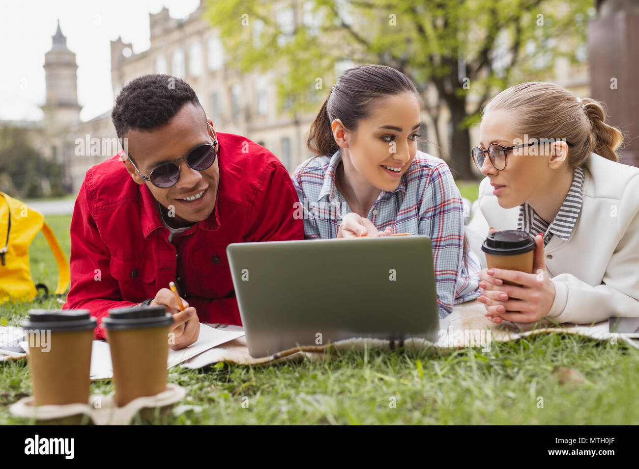 Three good-looking students lying in the grass Stock Photo - Alamy