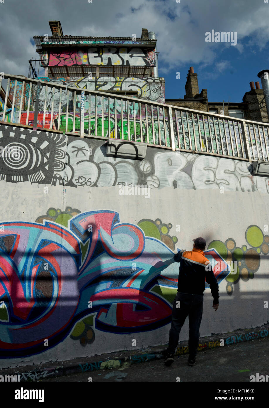 Graffiti artist painting on walls near Waterloo station in London ...
