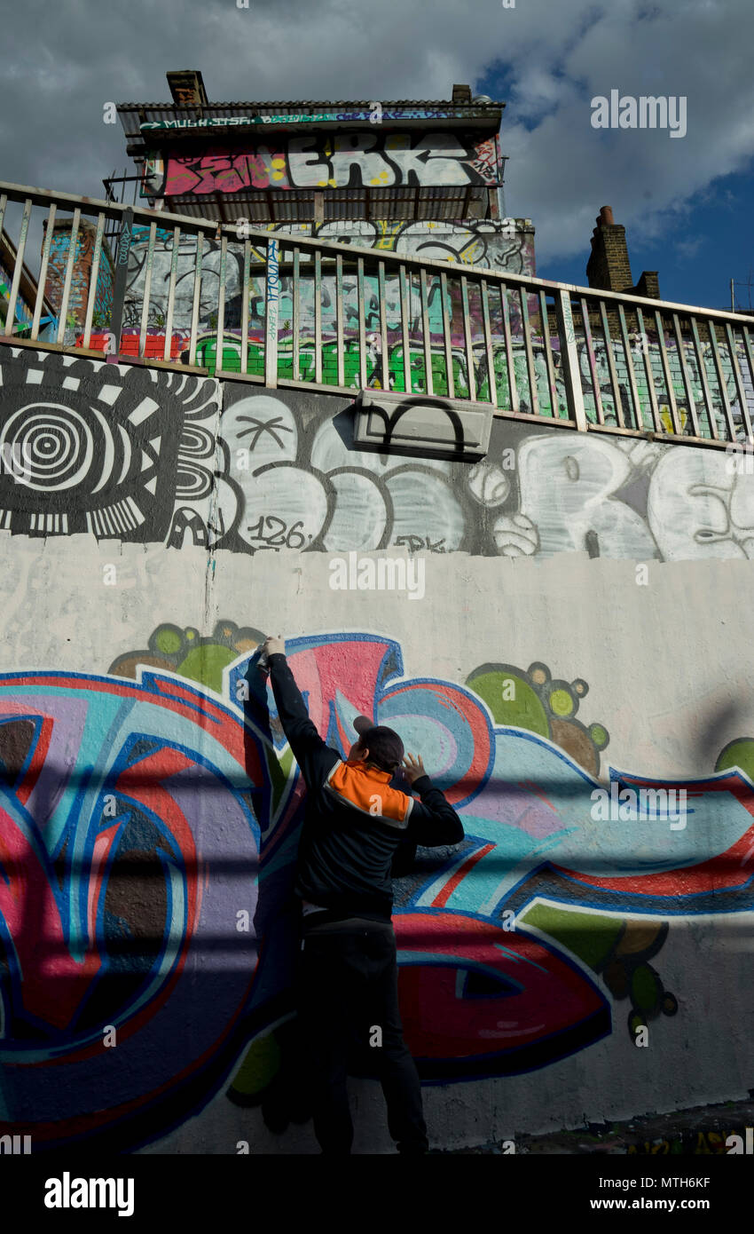 Graffiti artist painting on walls near Waterloo station in London ...
