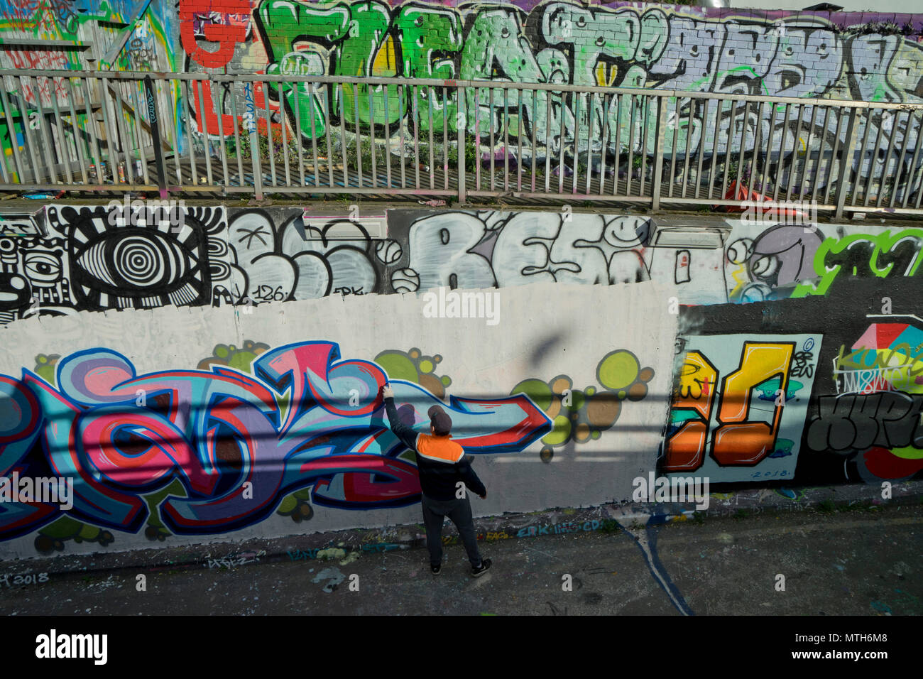 Graffiti artist painting on walls near Waterloo station in London ...