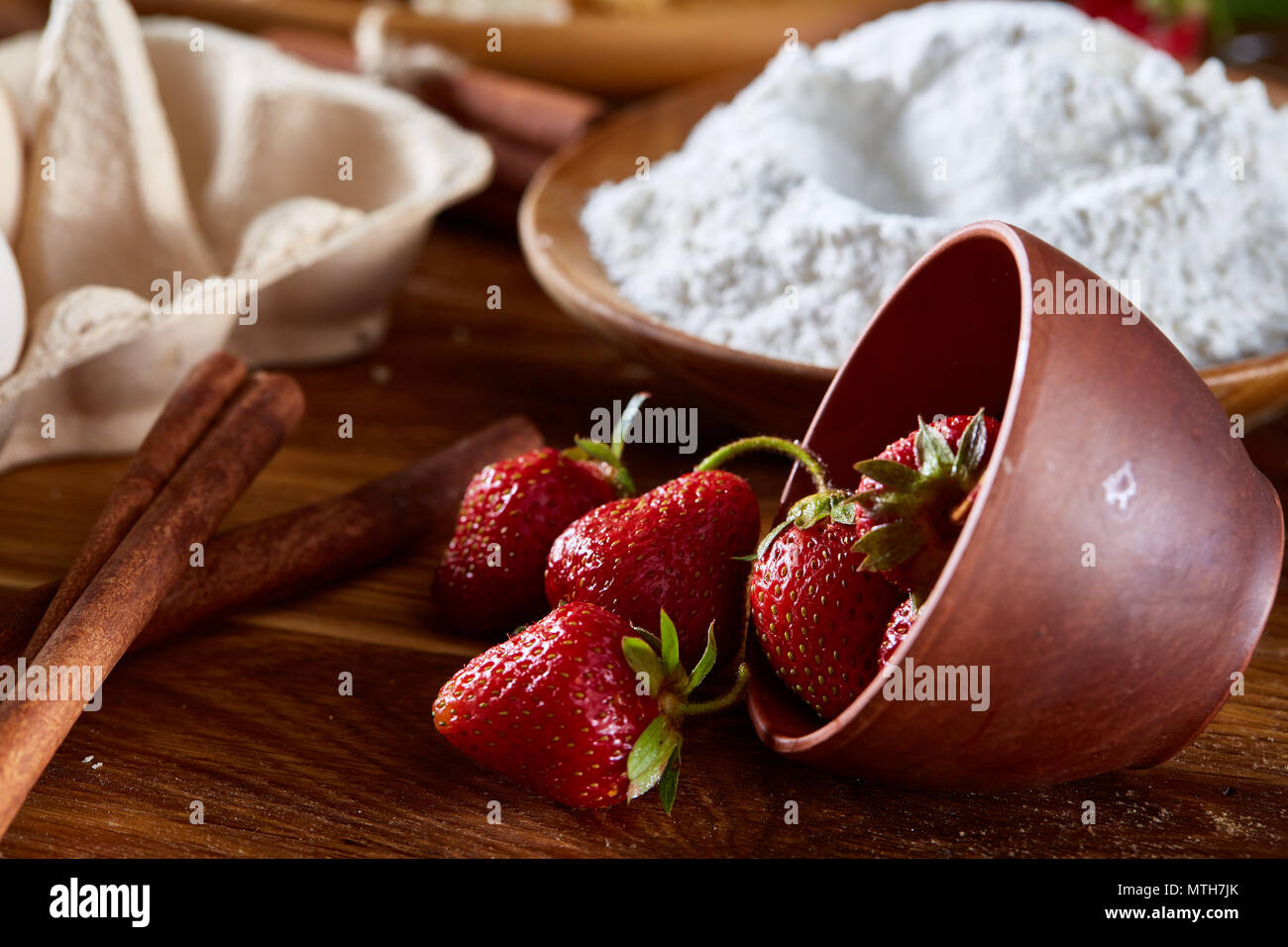 Red fresh strawberry in an overturned bowl on baking background, close ...