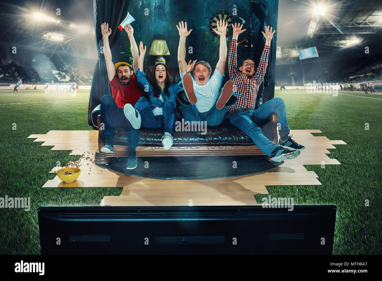 Soccer football fans sitting on the sofa and watching TV in the middle ...