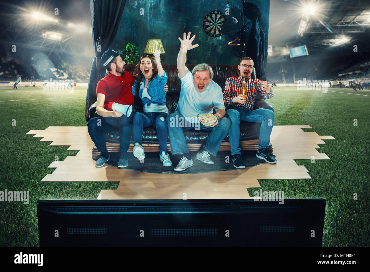 Soccer football fans sitting on the sofa and watching TV in the middle ...