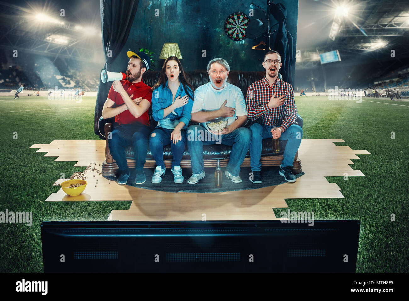 Soccer football fans sitting on the sofa and watching TV in the middle ...