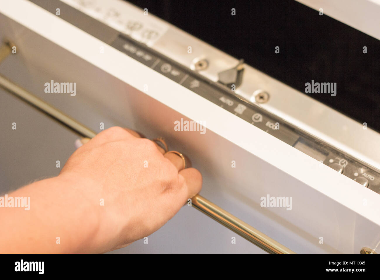 A young woman opens the lid of a dishwasher for washing dishes Stock ...