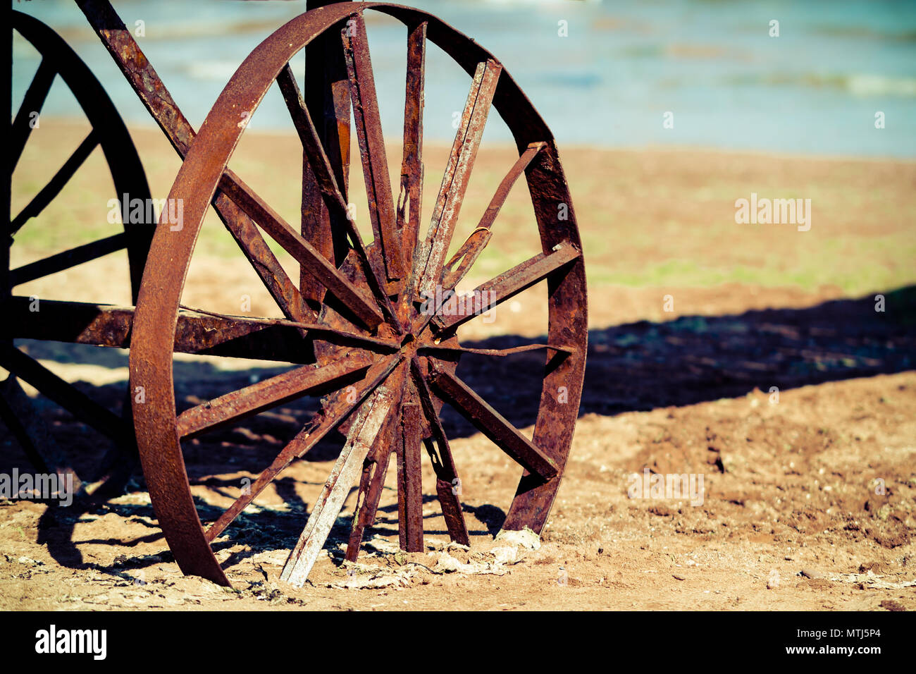 Old Rusty Metal Cart Wheel & Axle on Bright Beach Stock Photo - Alamy