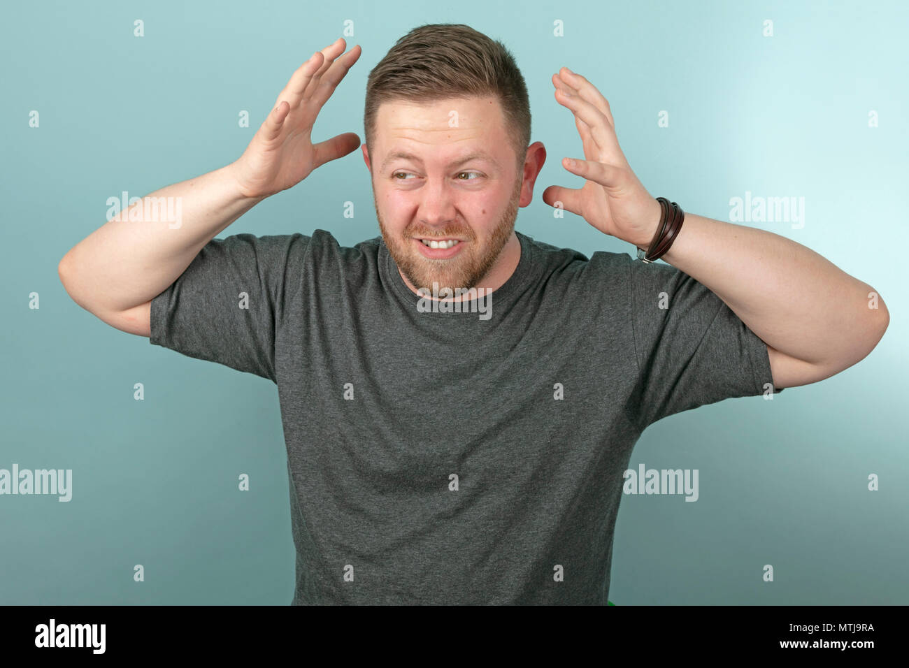 Frustrated angry man snarling and gesturing with his hands either side ...