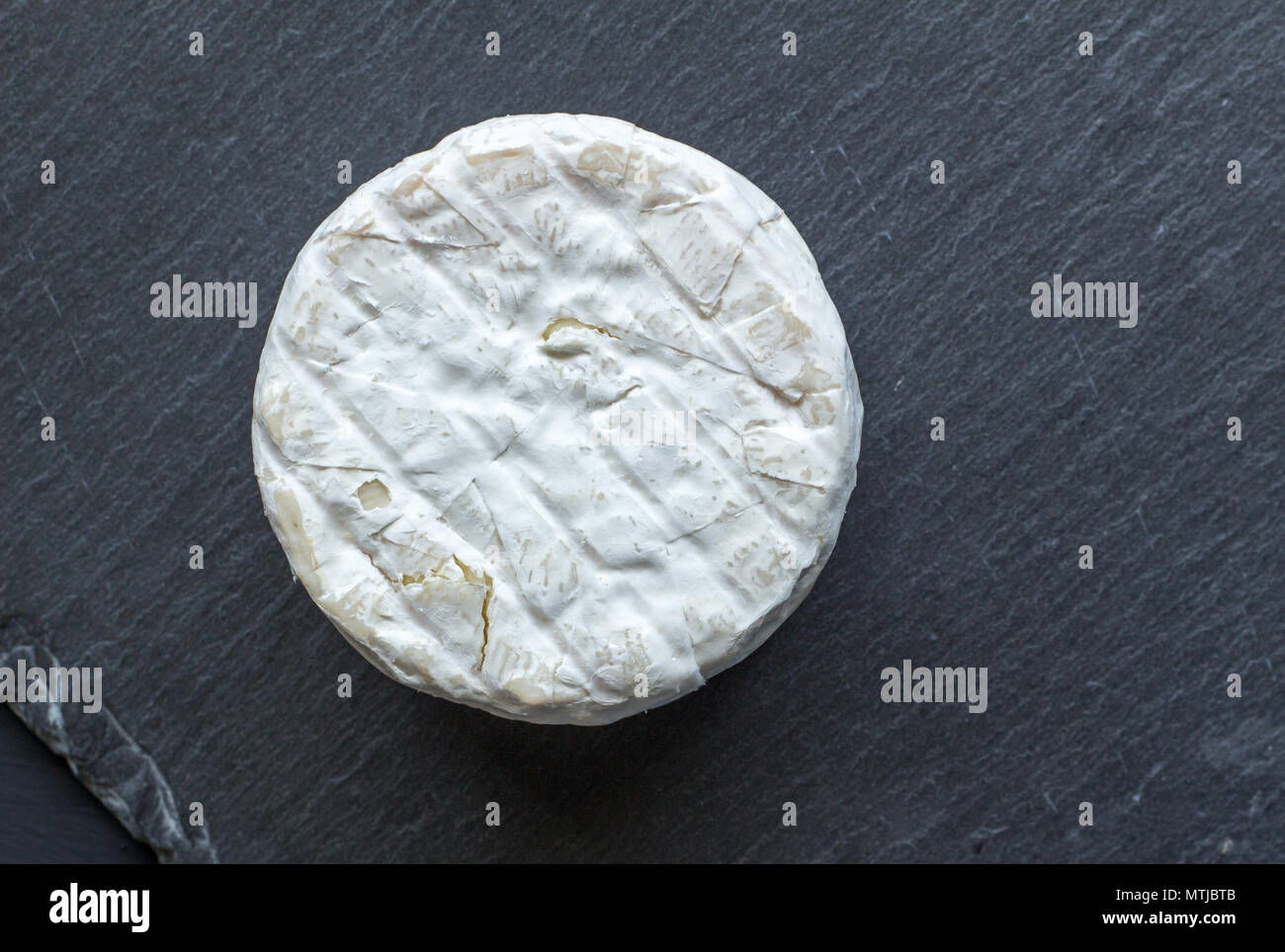 Whole round camembert cheese isolated on black slate board - top view ...