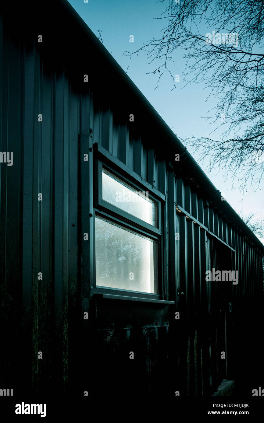 Light coming from a window in a sinister looking building at night ...