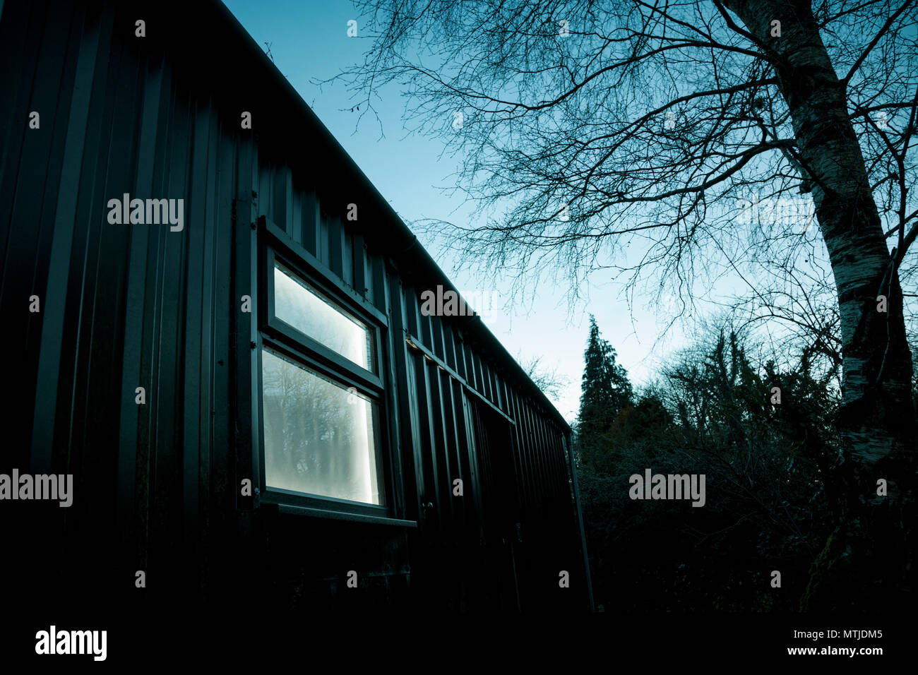 Light coming from a window in a sinister looking building at night ...