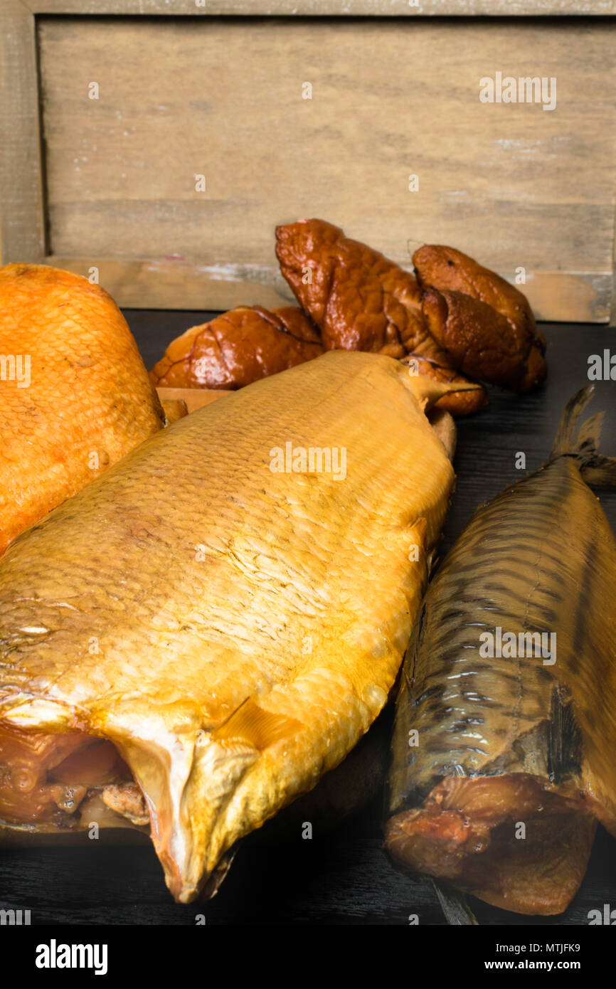 Smoked fish, mackerel, sig, perch and cod roe on the black wooden table ...