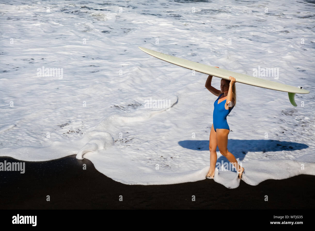 Sporty Girl In Bikini With Surf Board Walk On Black Sand Beach Young