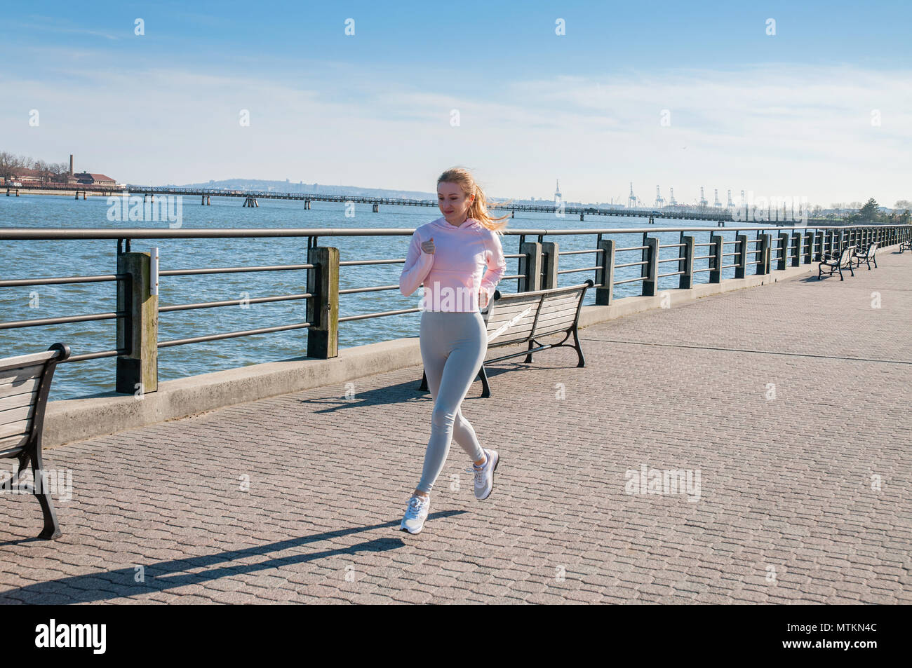 Young girl in sportswear jogging on the quay near the ocean. Workout on ...