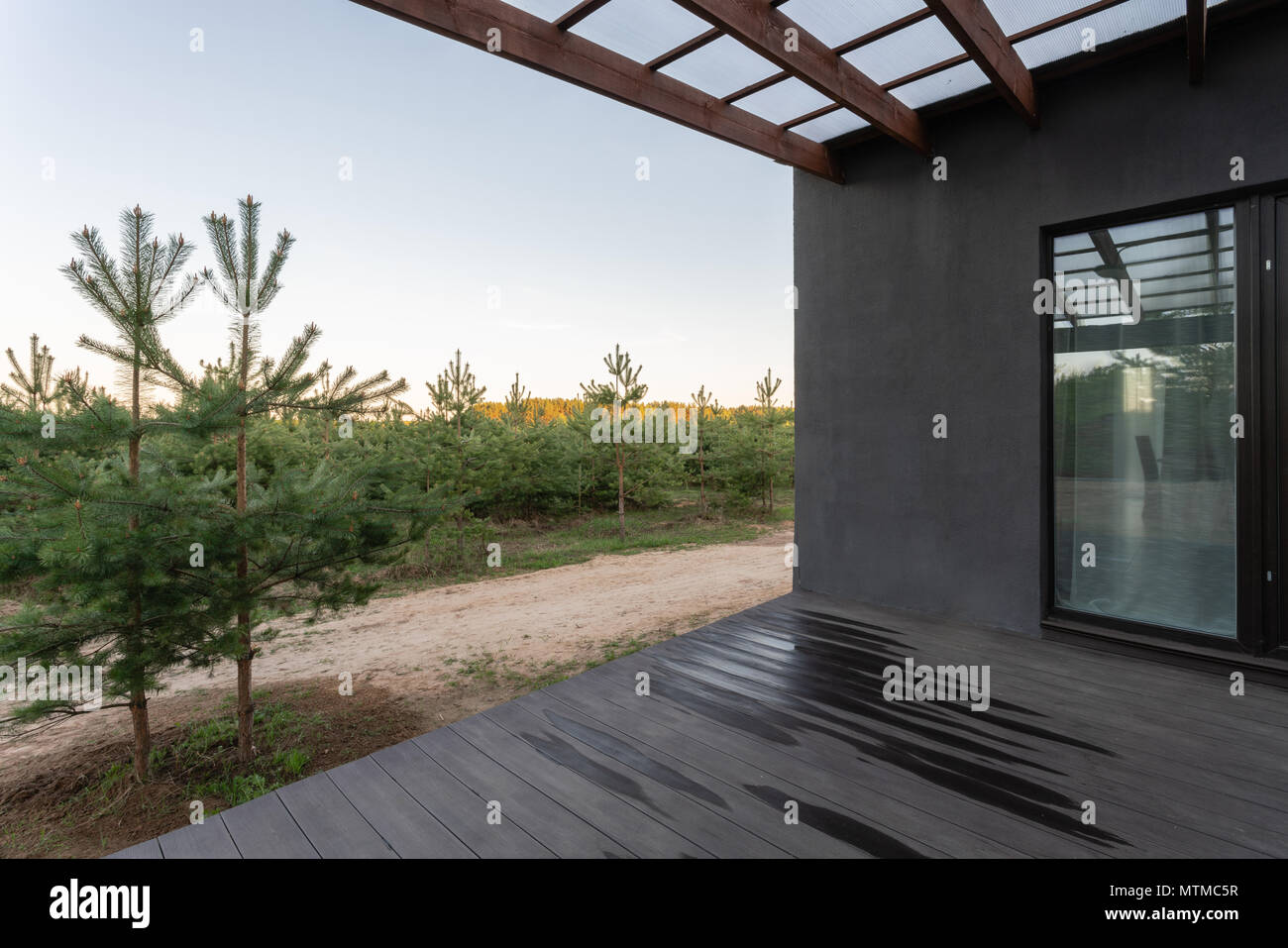 Side view of an open veranda in front of a modern forest cottage. Pine ...