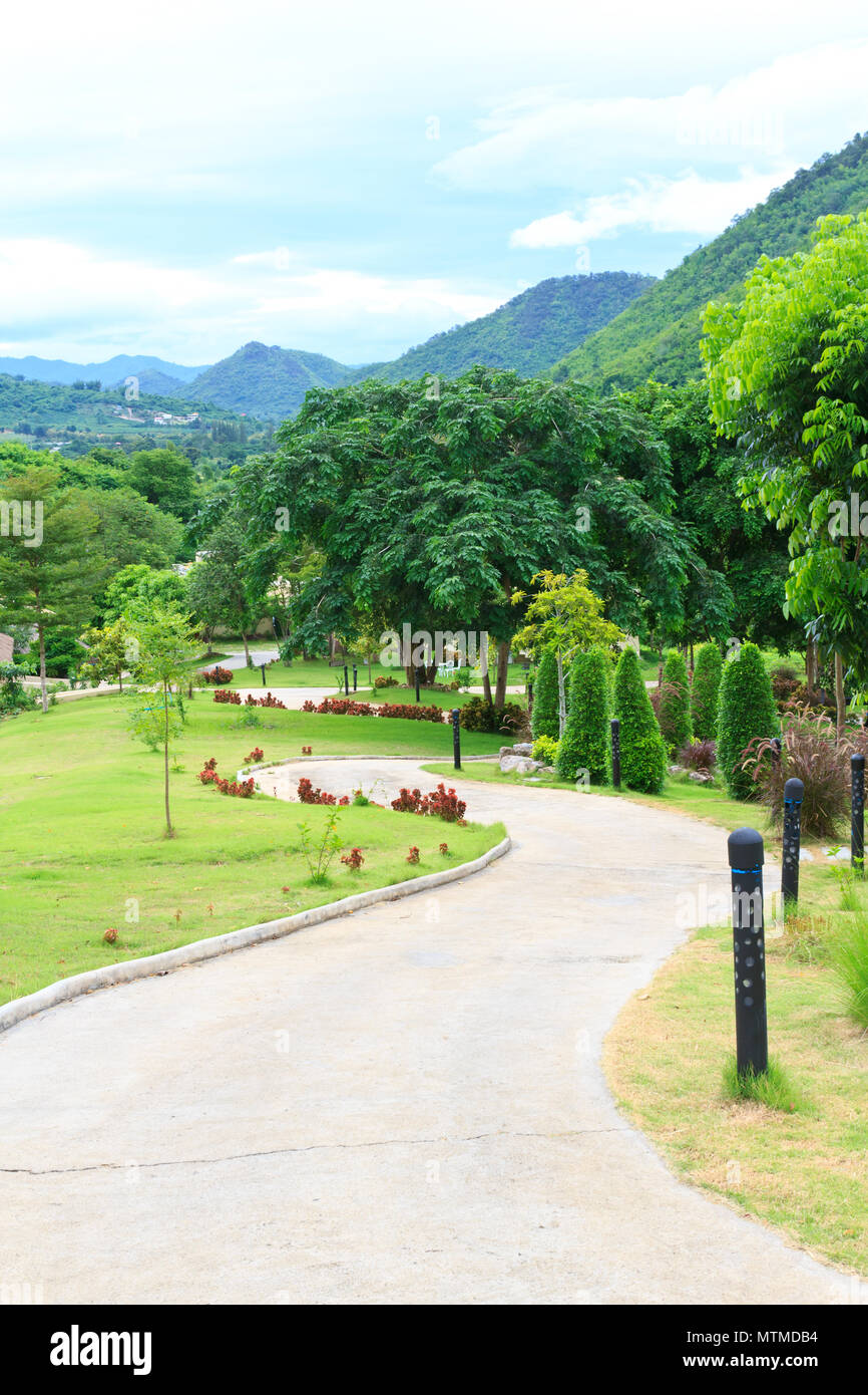 Pathway through a green garden with mountain background Stock Photo - Alamy