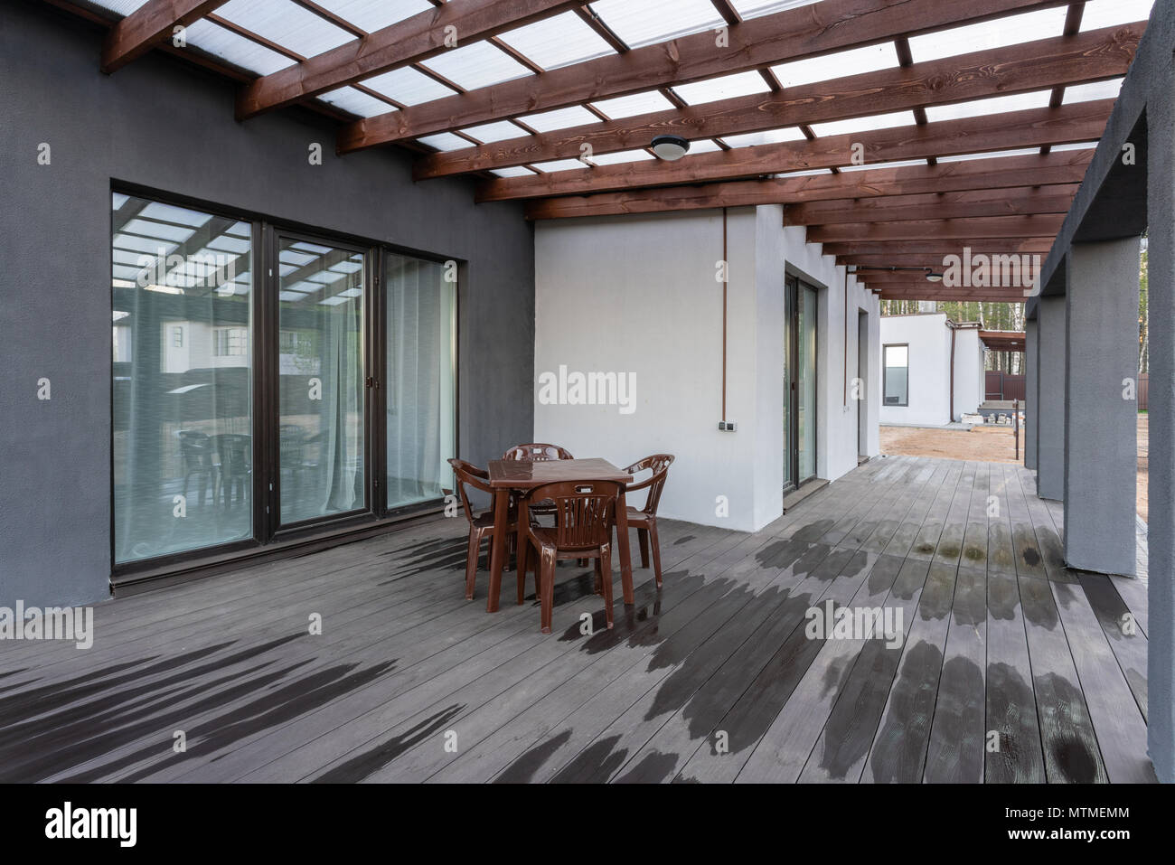 Side view of an open veranda in front of a modern forest cottage. Pine ...