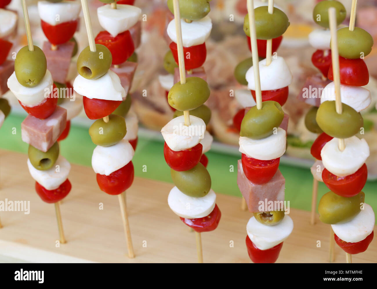 big skewers with olives, mozzarella cheese mortadella and red cherry ...
