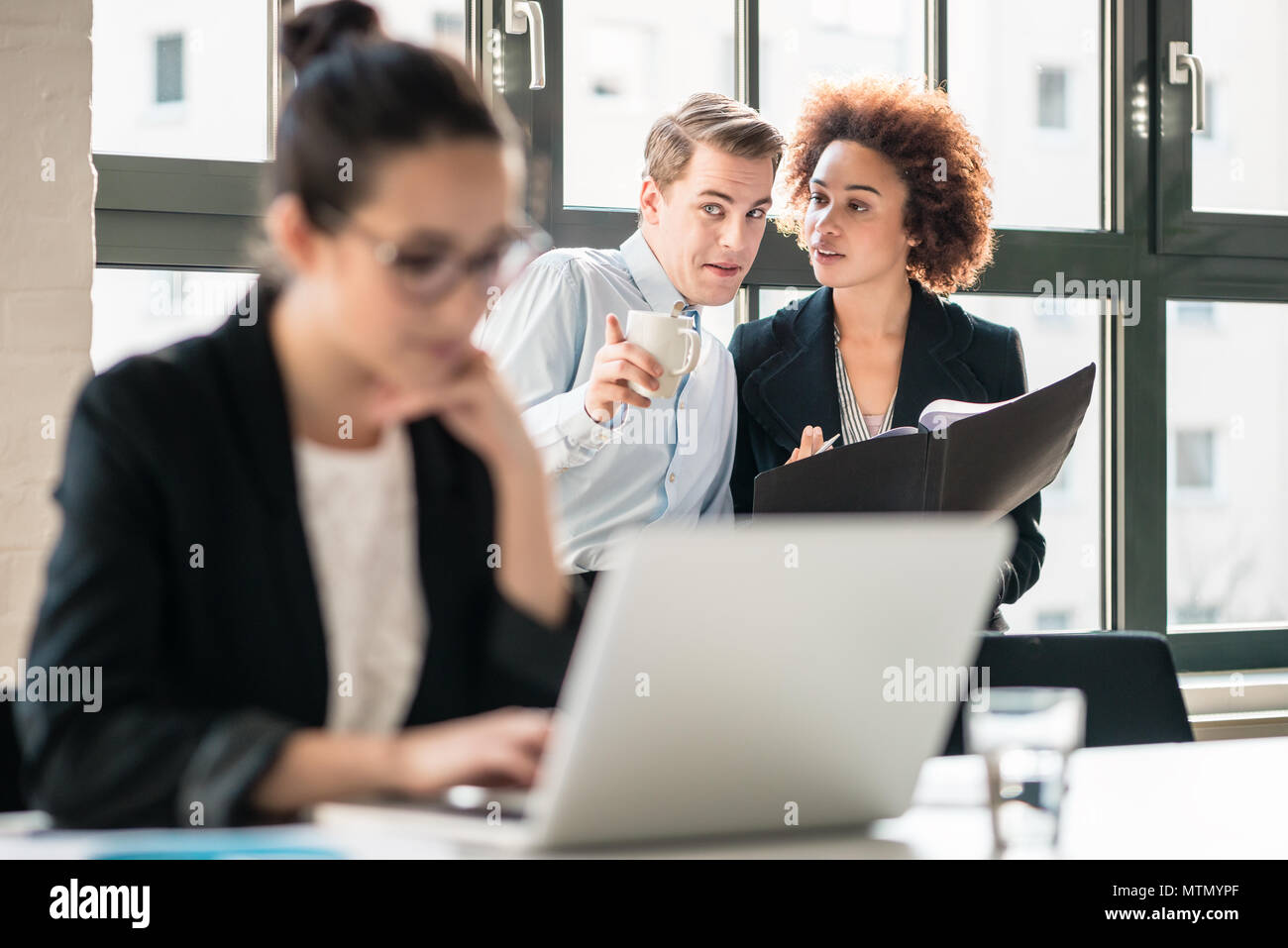 Two young malicious employees gossiping about their hard-working ...