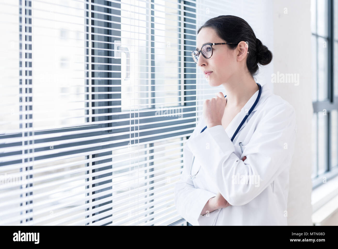 Side view portrait of a young female doctor daydreaming while looking ...