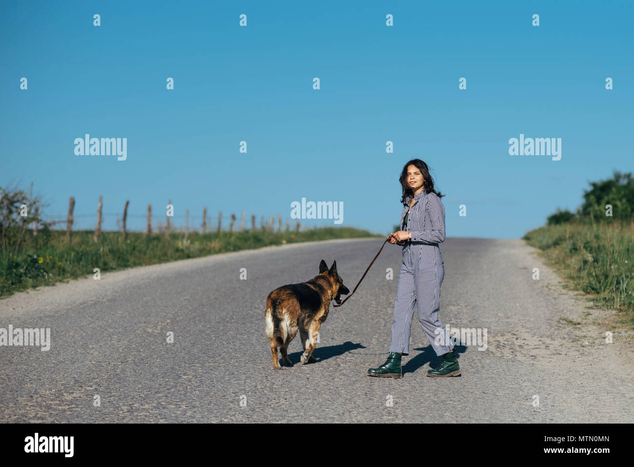 A pretty girl leads a dog next to her on the road Stock Photo - Alamy