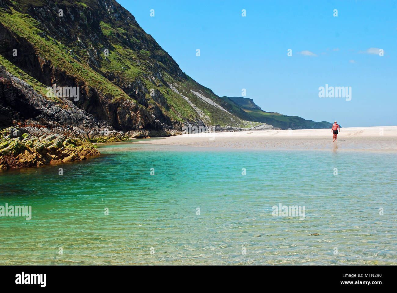 A man contemplates a swim in aquamarine waters at Maghera beach, Ardara ...