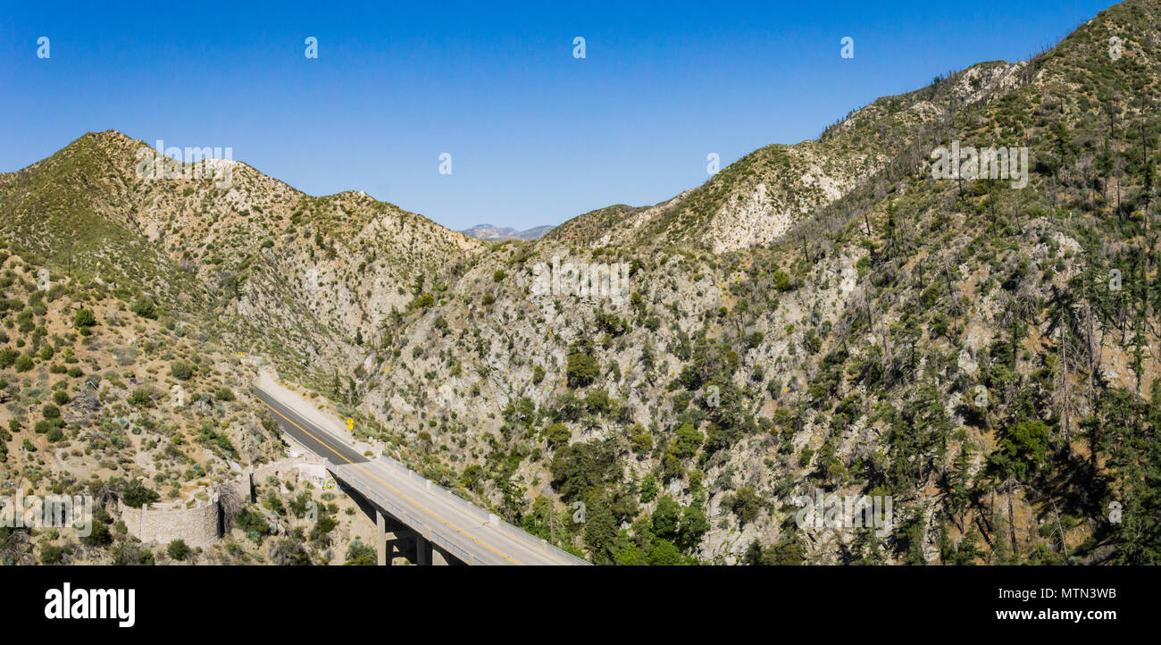 Panoramic view of rocky desert mountains above a desert road and bridge ...