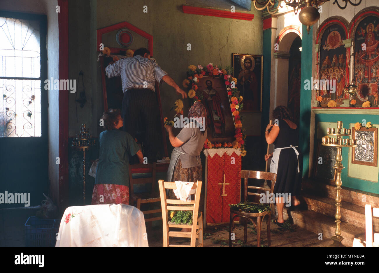 People clean a rural church and decorate the icons with flowers on the ...