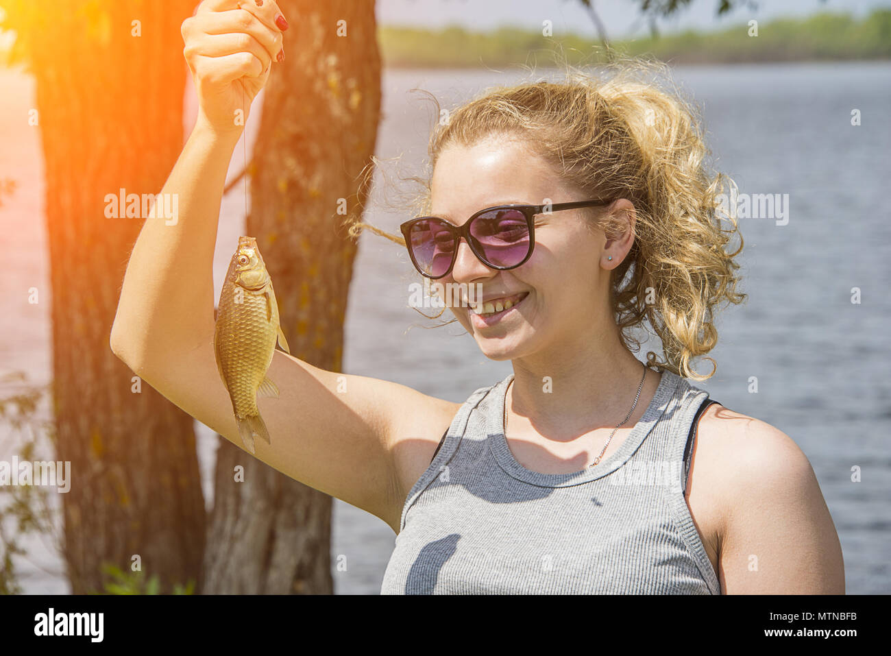 girl holding a fish caught in her hand ,rejoicing and smiling Stock ...