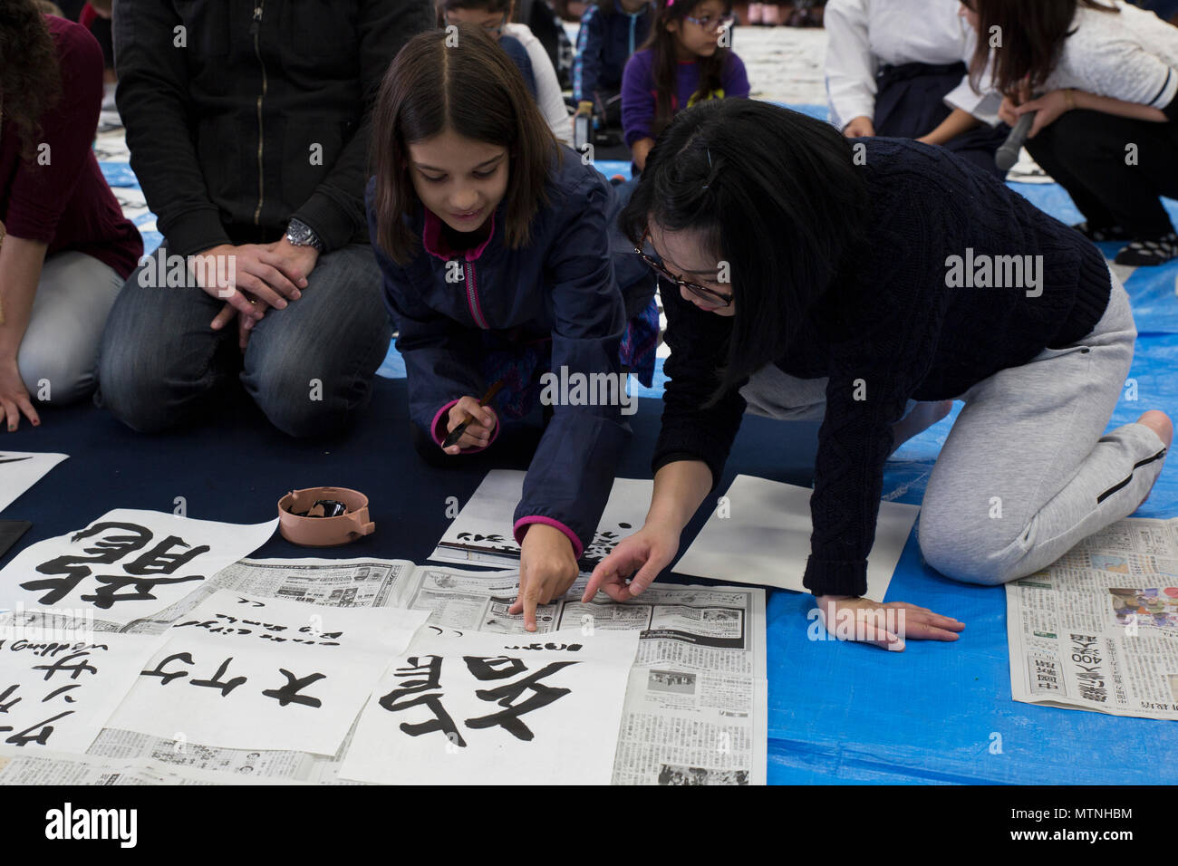 Yamamoto Yuko, a local calligraphy instructor, helps a child from ...