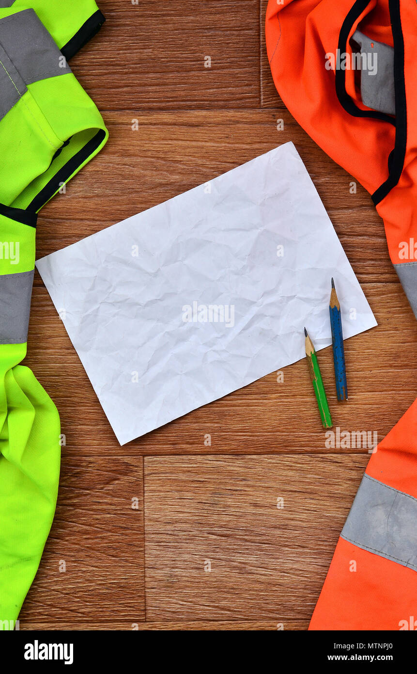 A crumpled sheet of paper with two pencils surrounded by green and ...