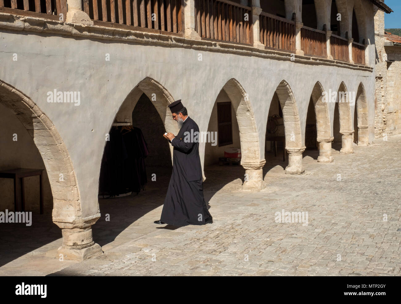 A priest walking across a courtyard at the Monastery of the Holy Cross ...
