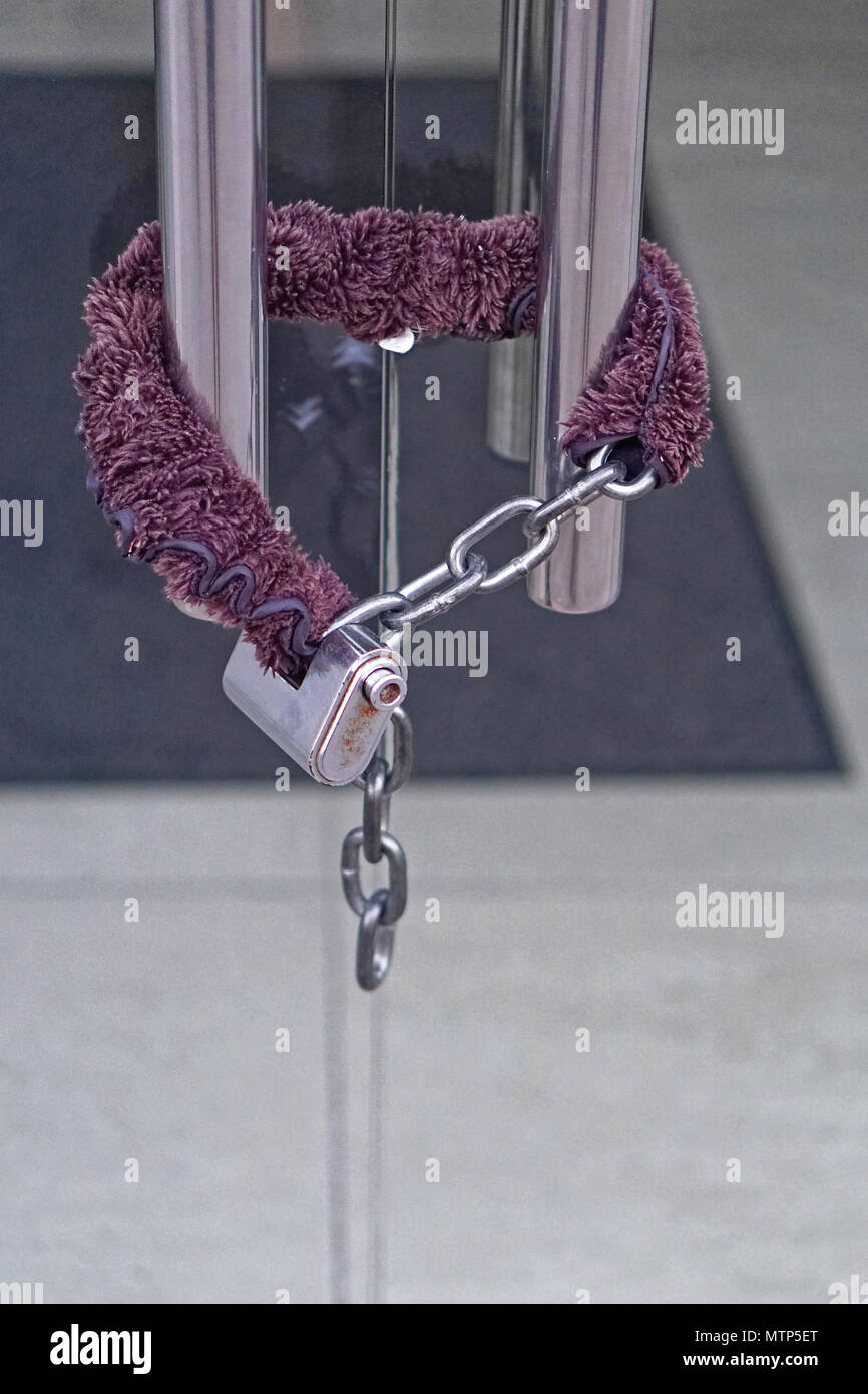 Padded chain with strong padlock at glas door Stock Photo - Alamy