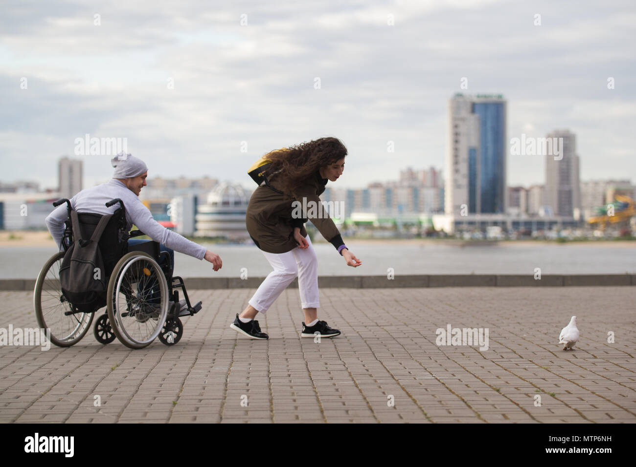 Disabled young man in wheelchair with young woman feeding pigeon Stock ...