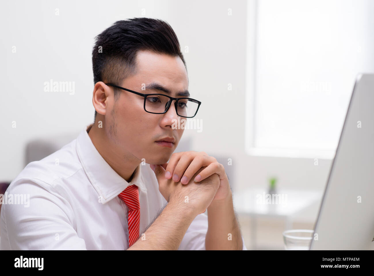Young stylish worker at office working with computer and thinking how ...