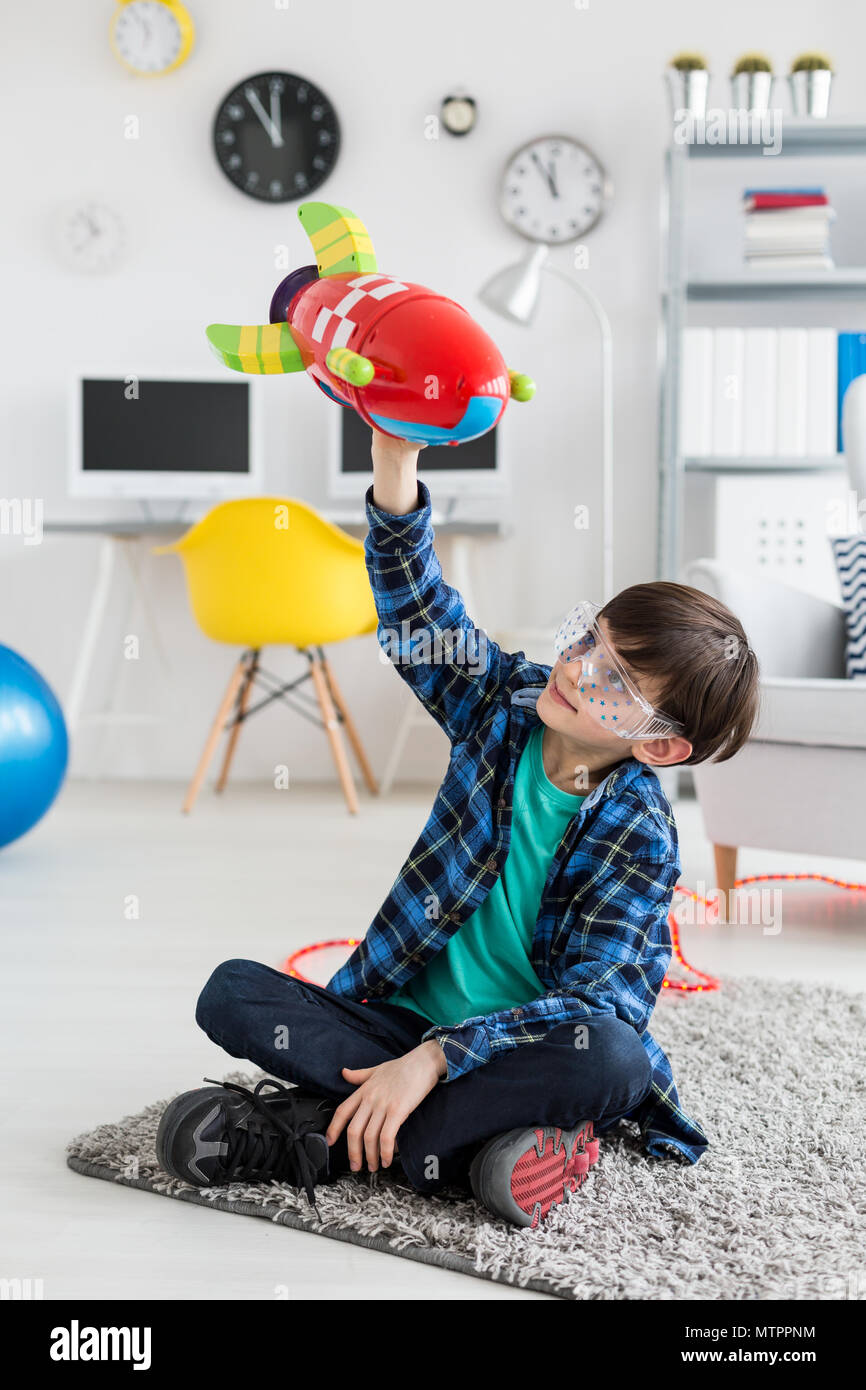 Shot of a little boy sitting on a floor and playing with a toy rocket ...