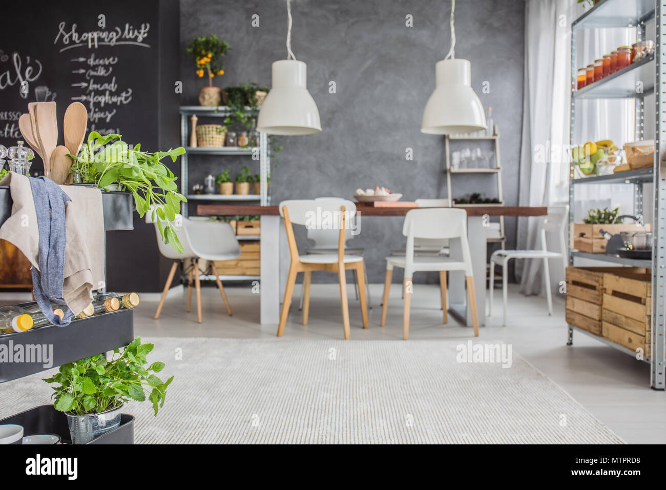 Spacious kitchen with dining table and fresh herbs Stock Photo - Alamy