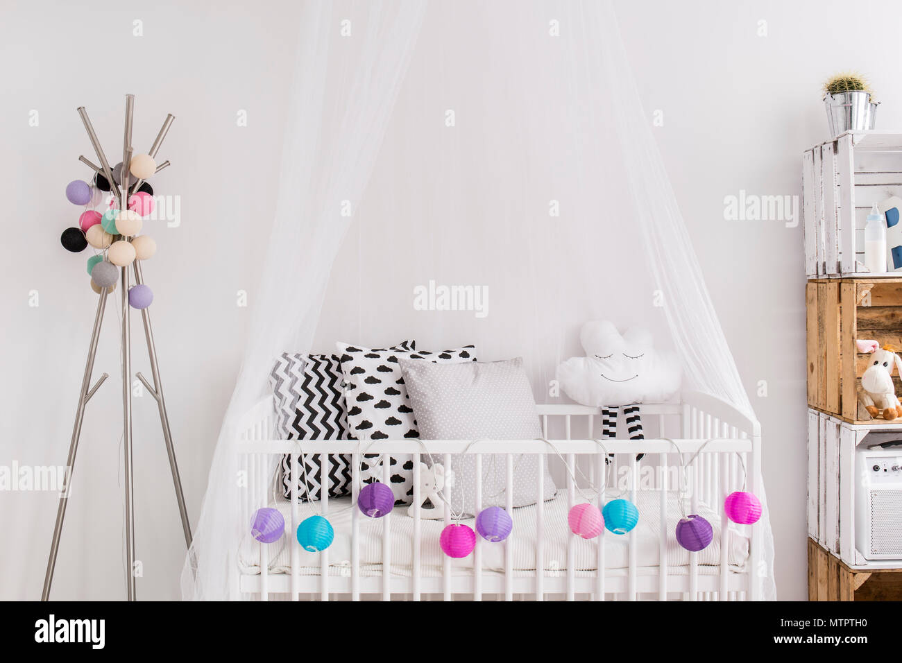 Simple white cradle decorated with colorful bulbs. In the cradle white ...
