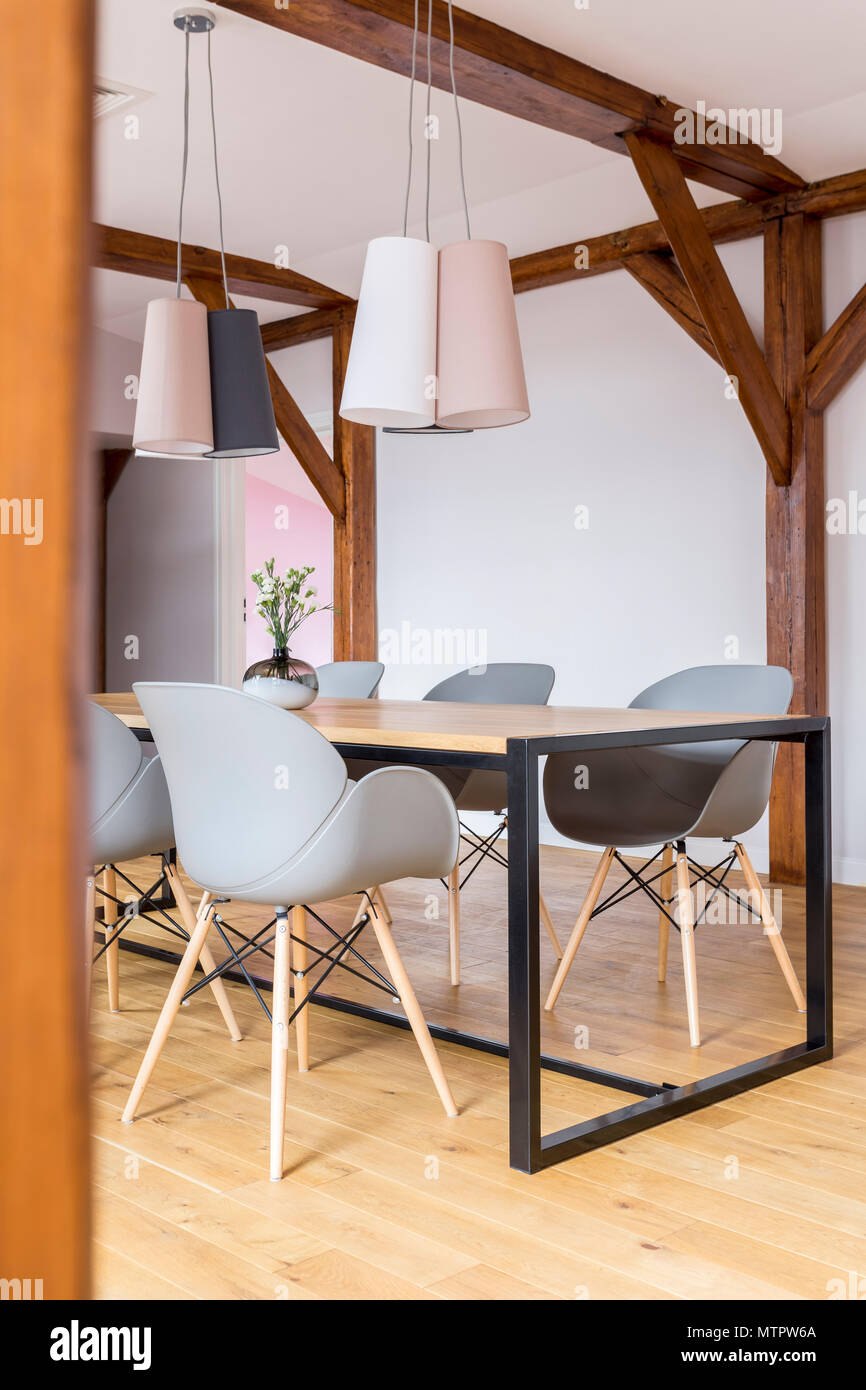 Designed lamps above dining table with grey chairs in spacious room ...