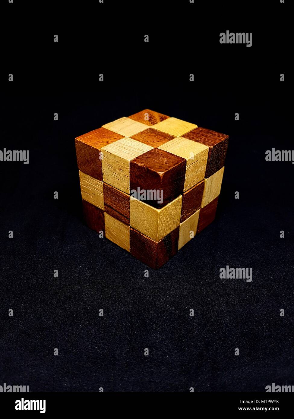 Wooden cube brain teaser on black background Stock Photo - Alamy