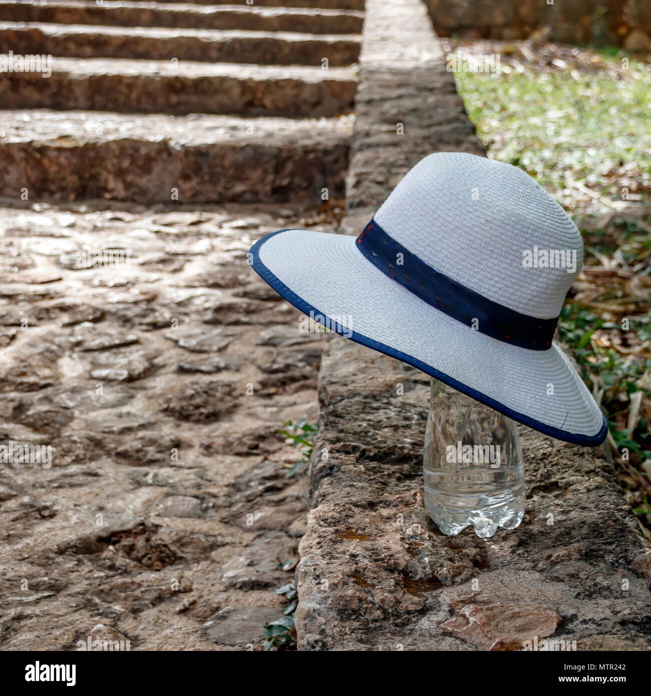 A bottle of water covered with a white female hat Stock Photo - Alamy