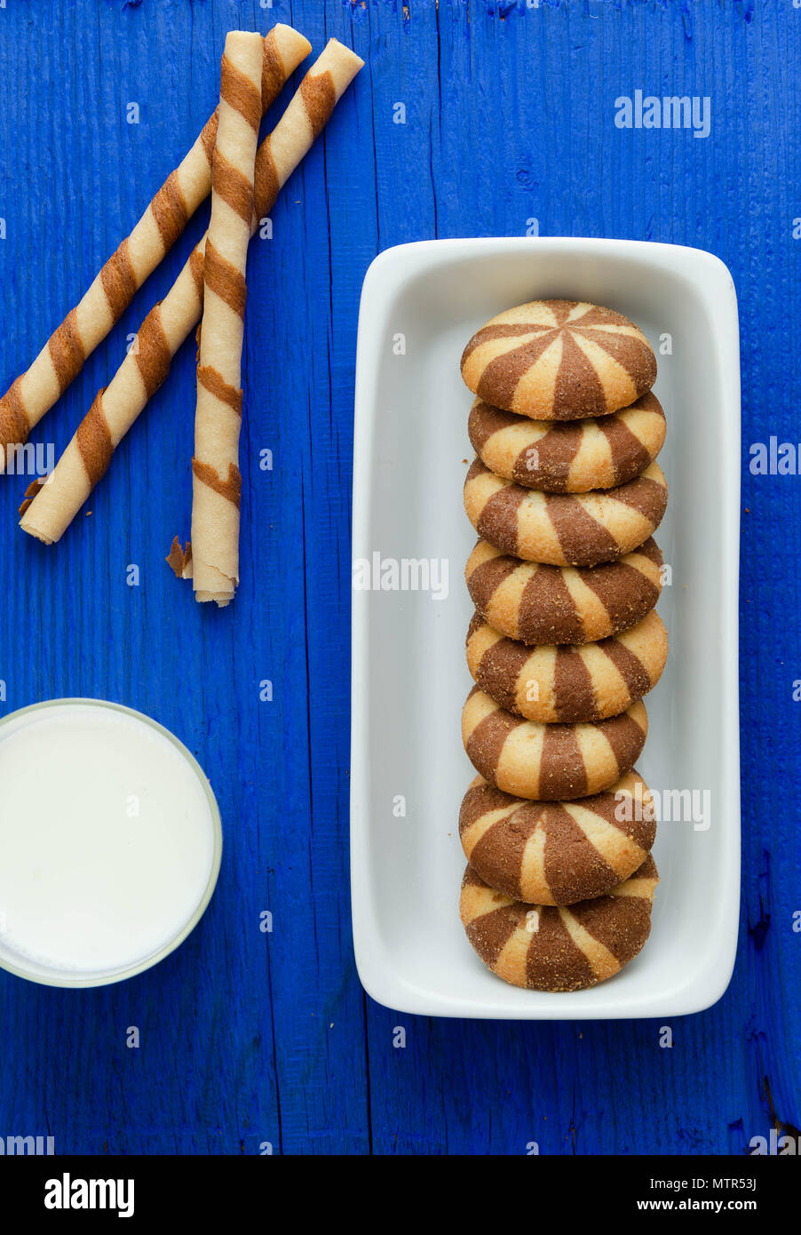 Striped chocolate wafer rolls and stake biscuits over blue background ...