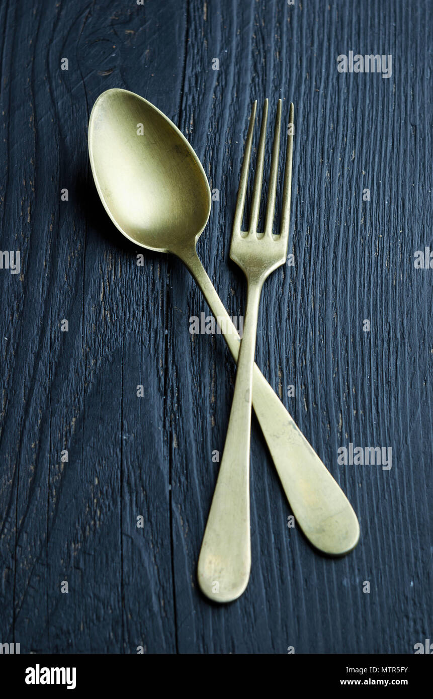 Golden spoon and a fork over black wooden table, top view Stock Photo ...